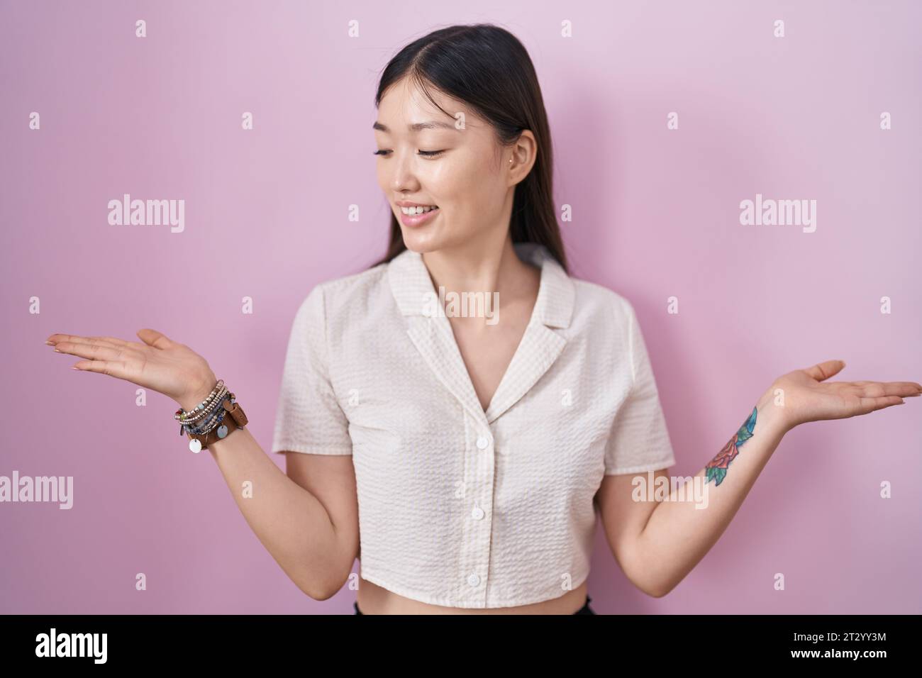 Chinese young woman standing over pink background smiling showing both ...