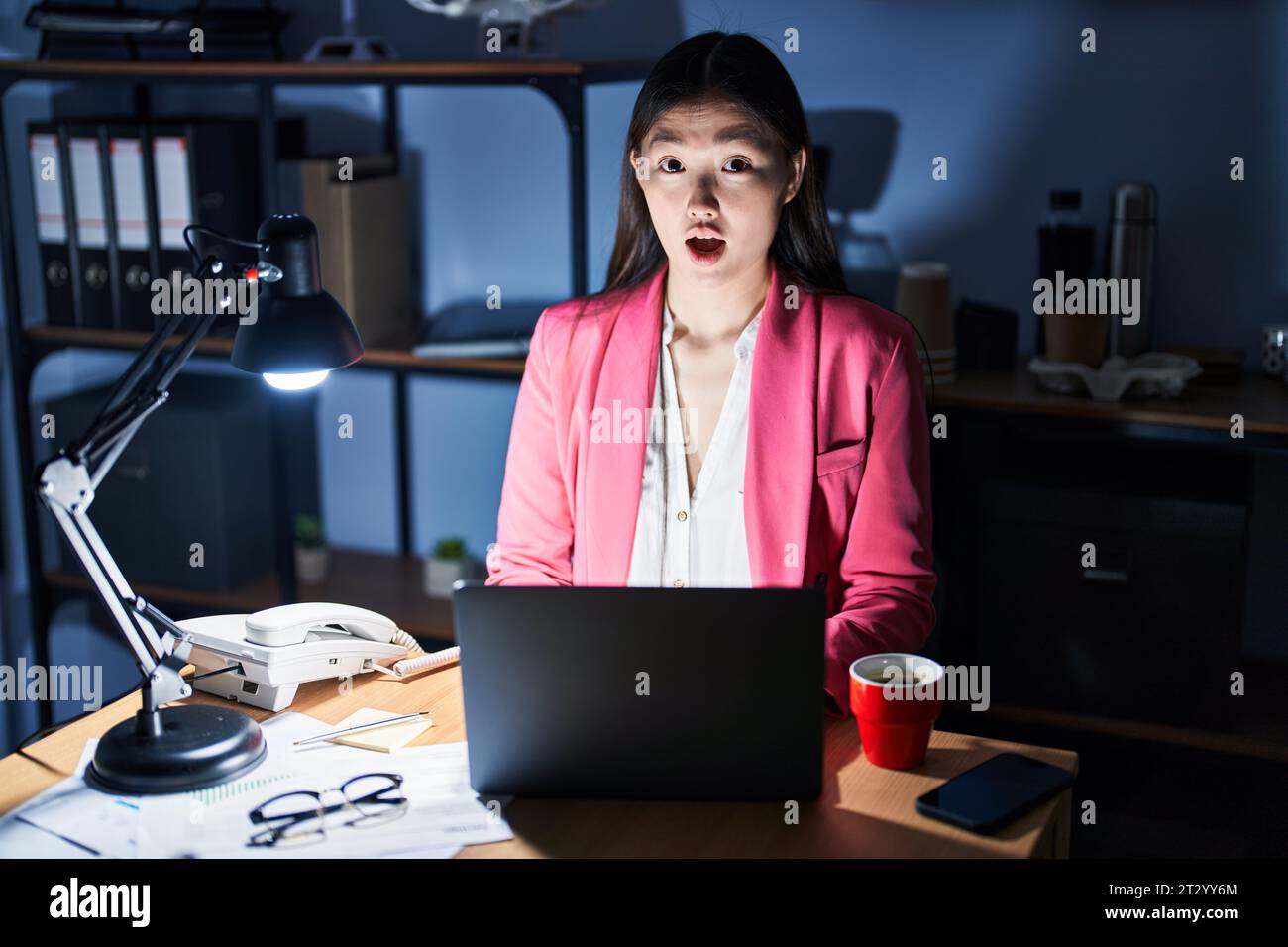 Chinese young woman working at the office at night afraid and shocked ...