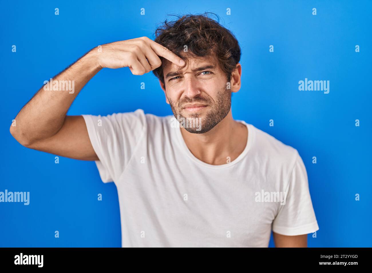 Hispanic young man standing over blue background pointing unhappy to ...