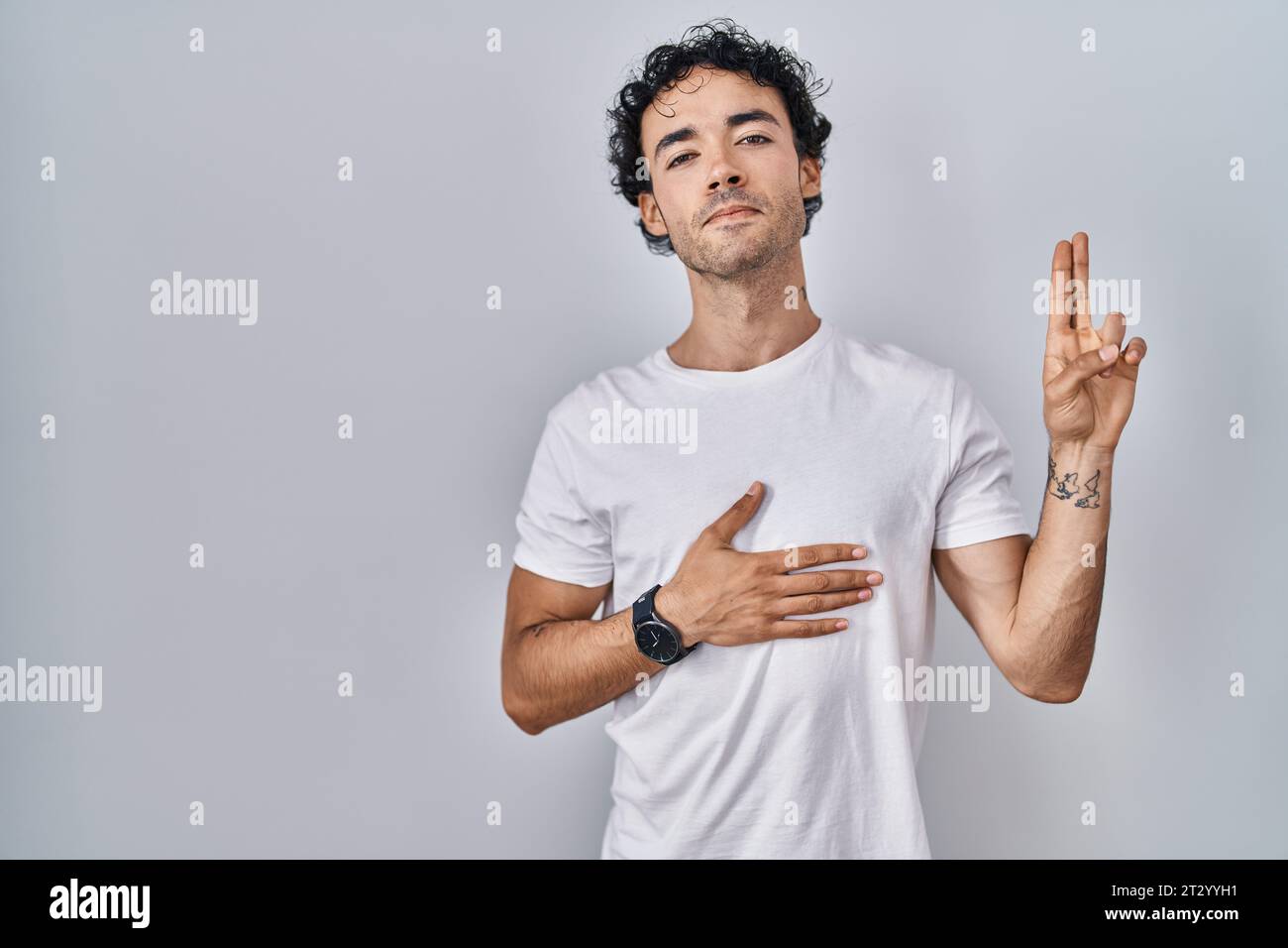 Hispanic man standing over isolated background smiling swearing with ...