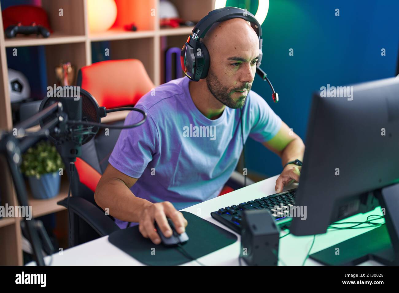 Young bald man streamer playing video game using computer at gaming ...