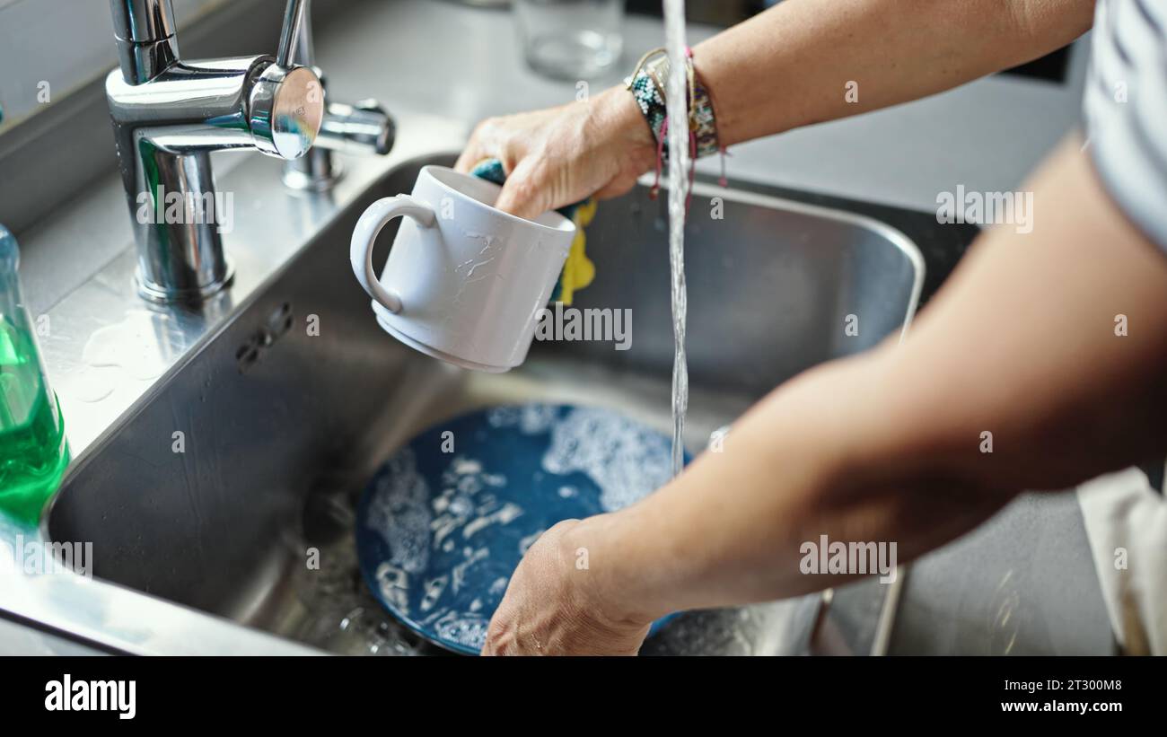Middle age hispanic woman washing plates at the kitchen Stock Photo - Alamy