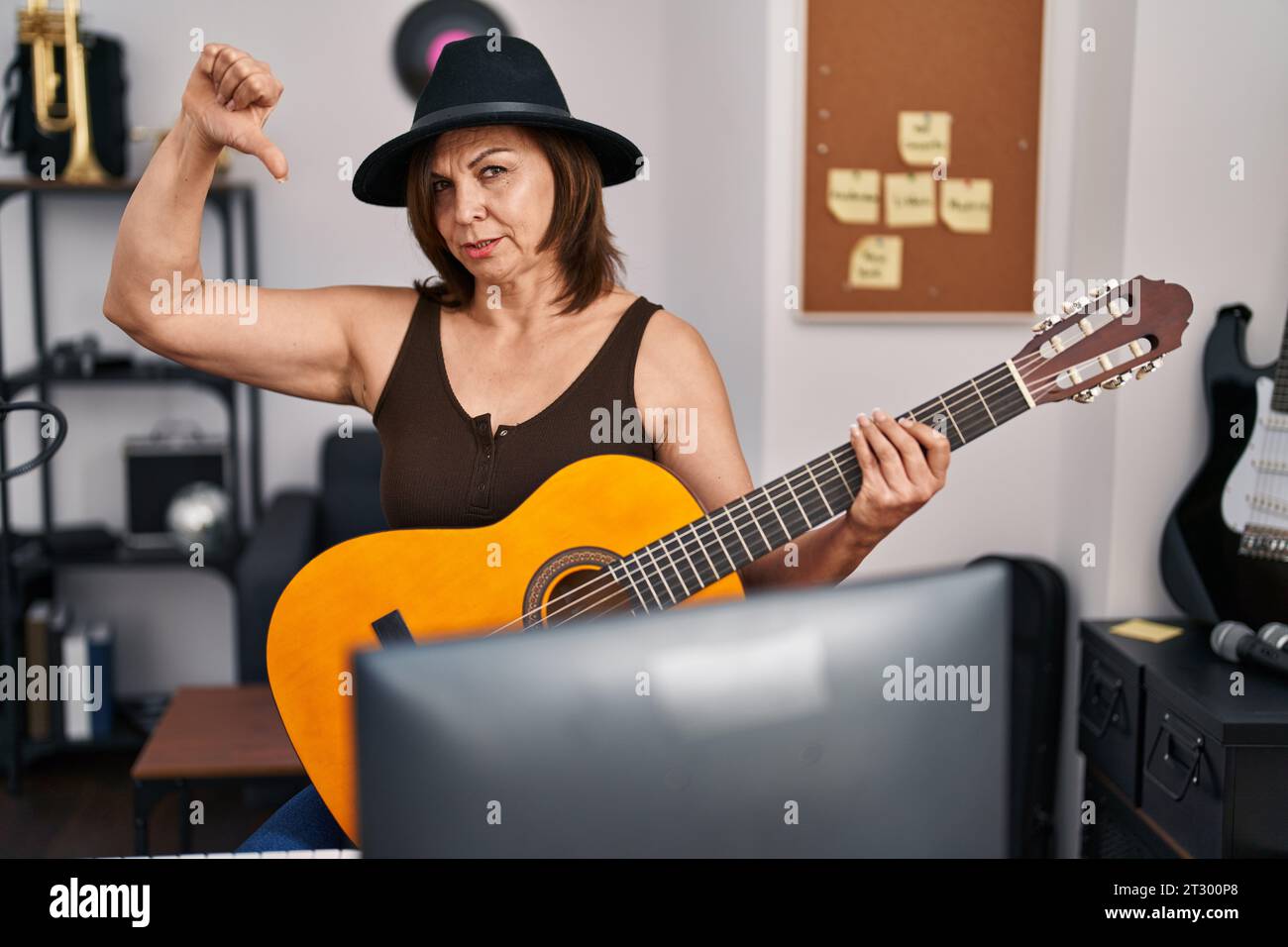 Middle age hispanic woman playing classic guitar at music studio with ...