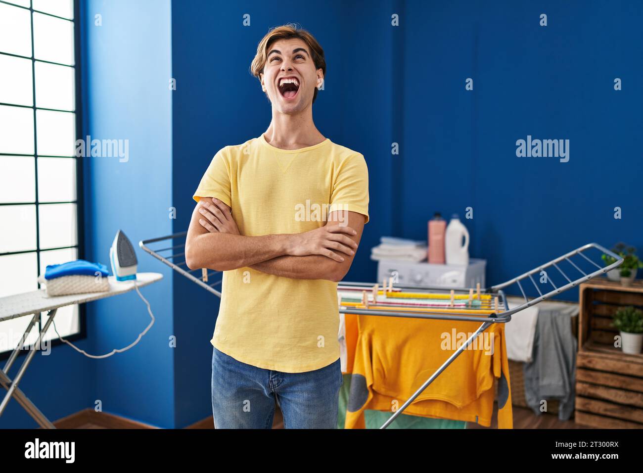 Young man doing laundry angry and mad screaming frustrated and furious ...