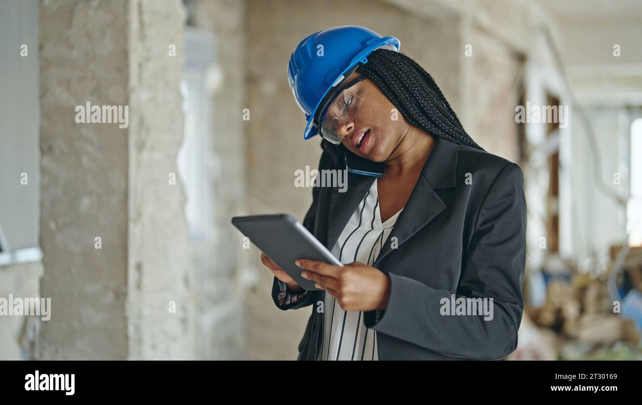 African american woman architect using touchpad talking on smartphone ...