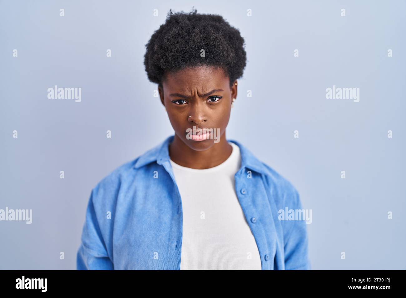 African american woman standing over blue background skeptic and ...