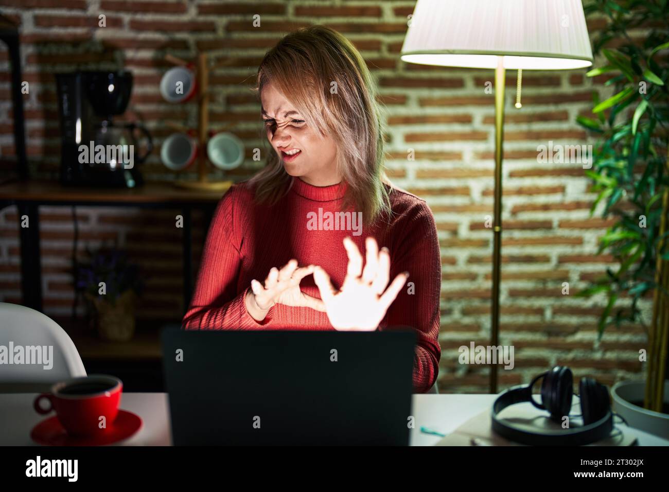 Blonde woman using laptop at night at home disgusted expression ...