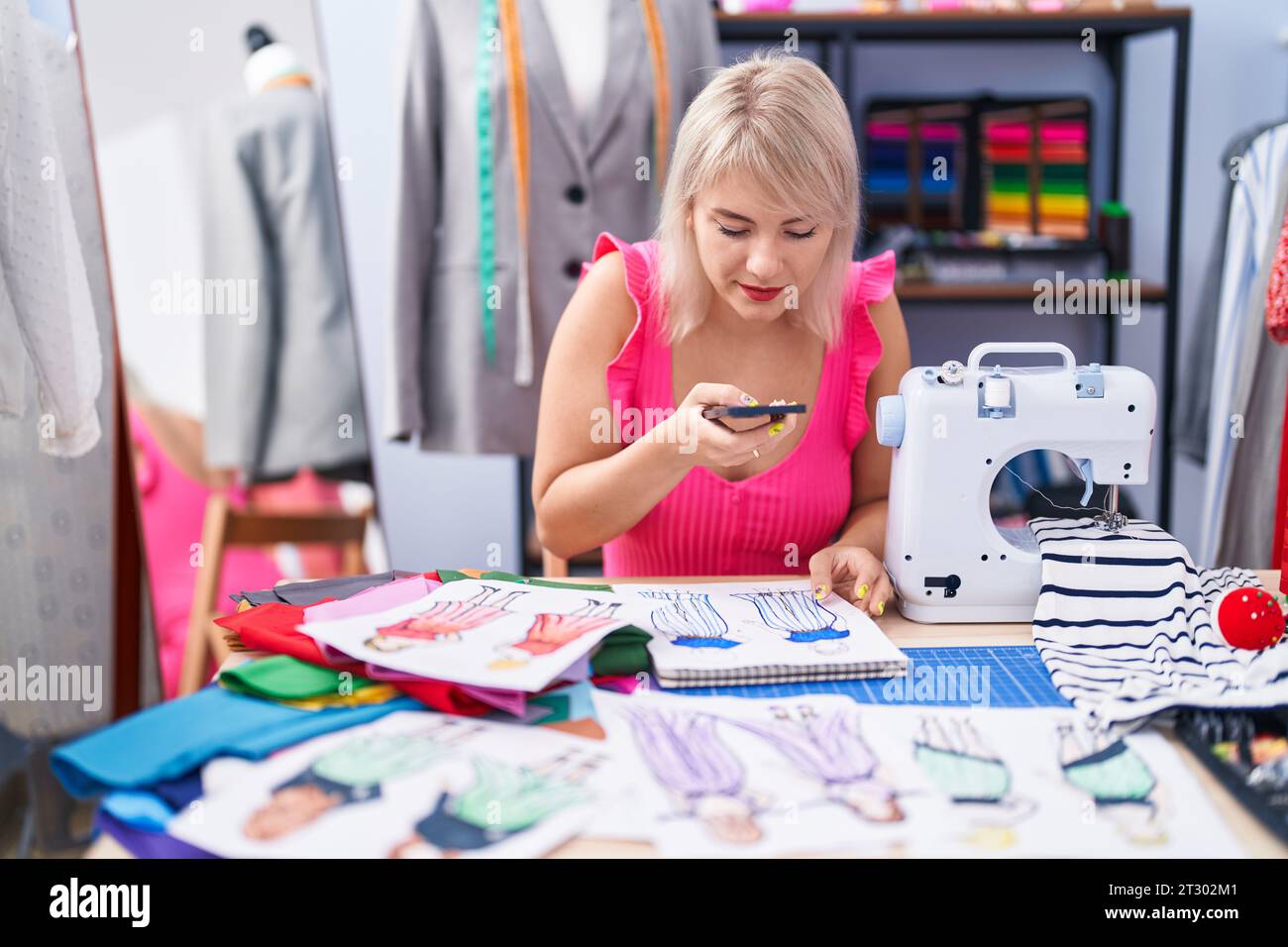 Young blonde woman tailor make photo by smartphone to clothing design ...