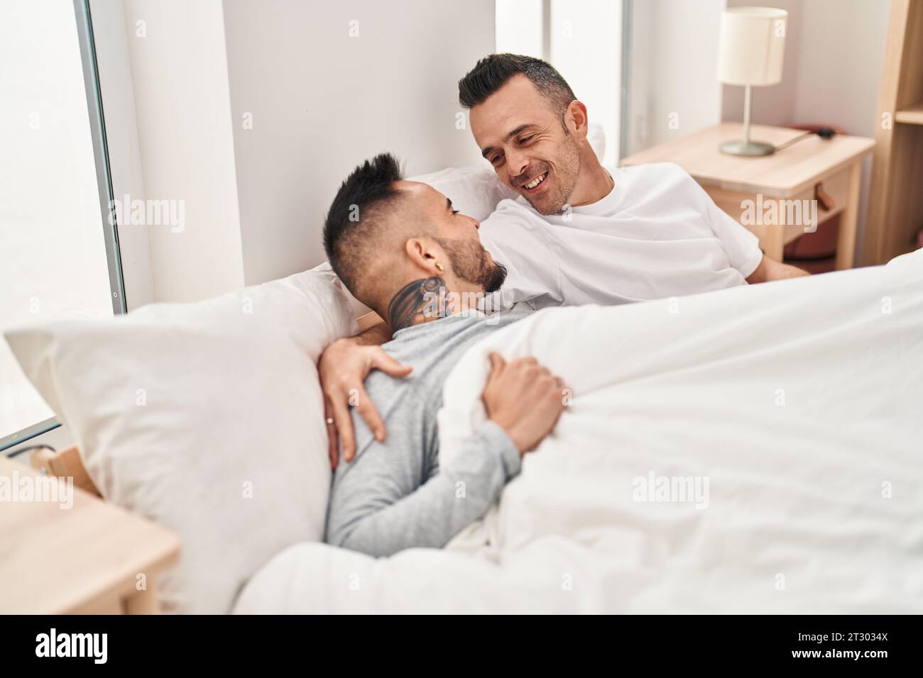 Two men couple lying on bed hugging each other at bedroom Stock Photo ...