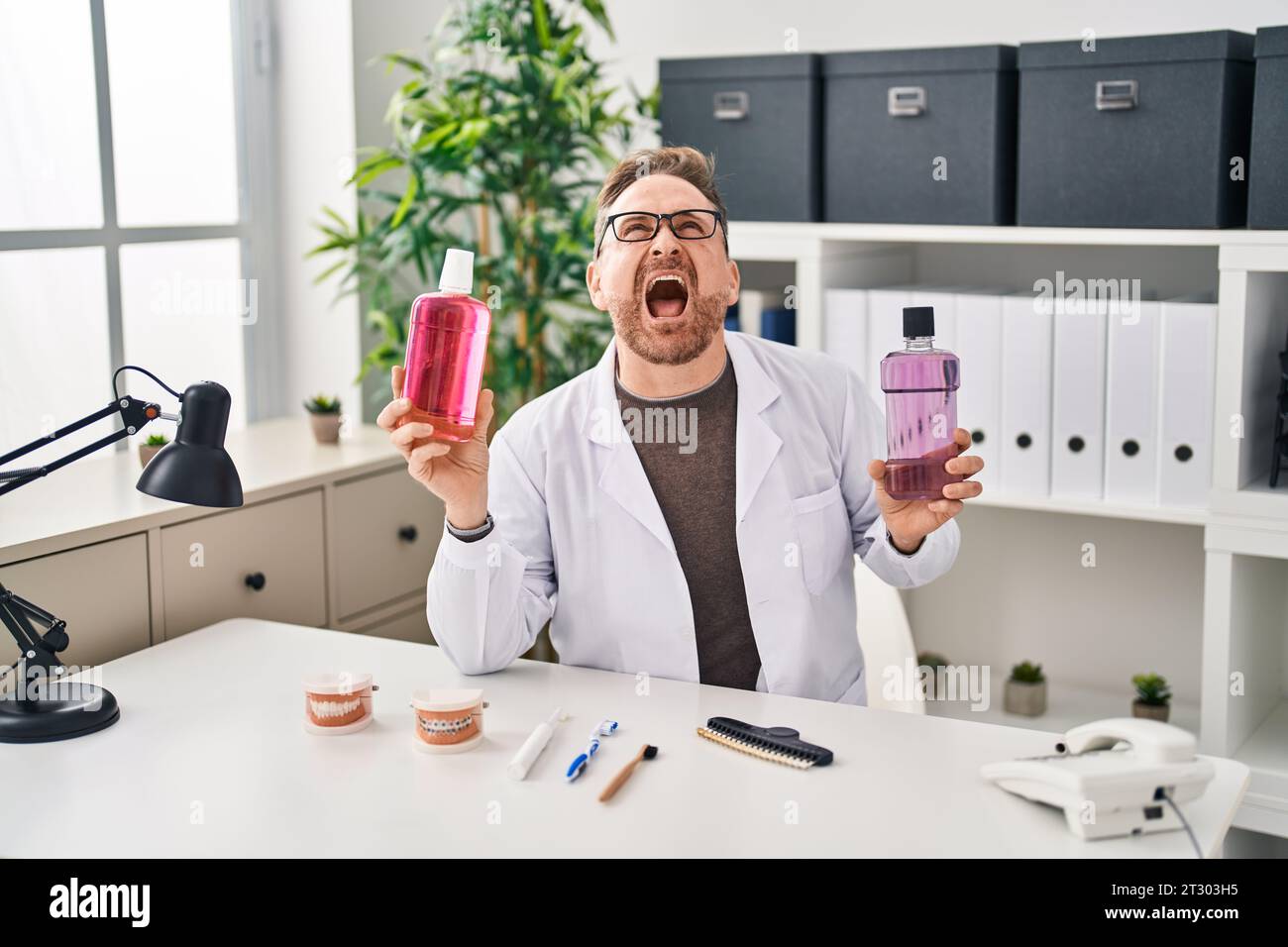 Middle age caucasian dentist man holding mouthwash for fresh breath ...