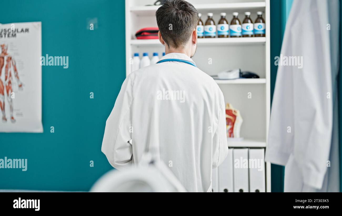 Young hispanic man doctor standing backwards at clinic Stock Photo - Alamy