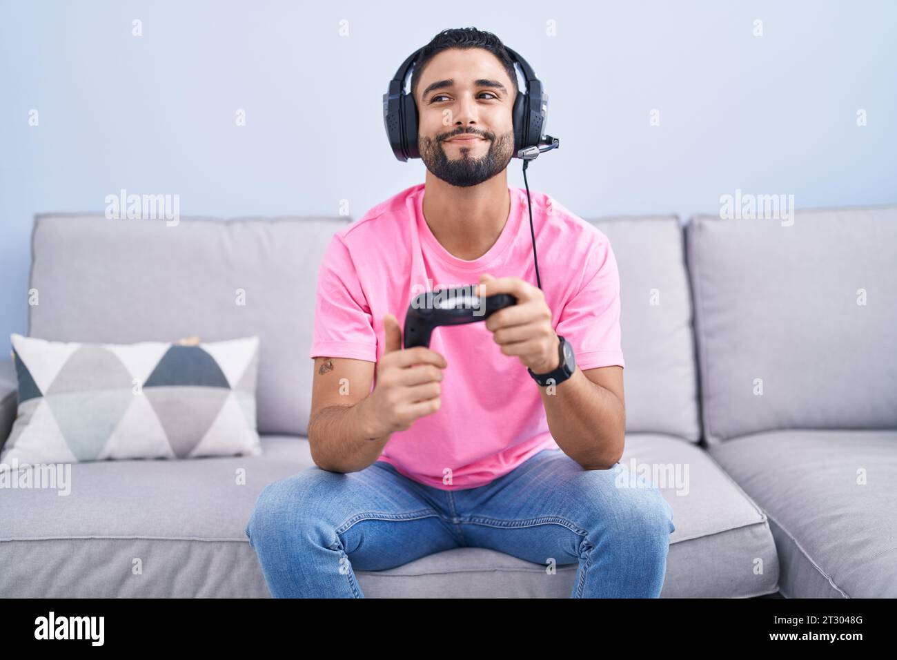 Hispanic young man playing video game holding controller sitting on the ...