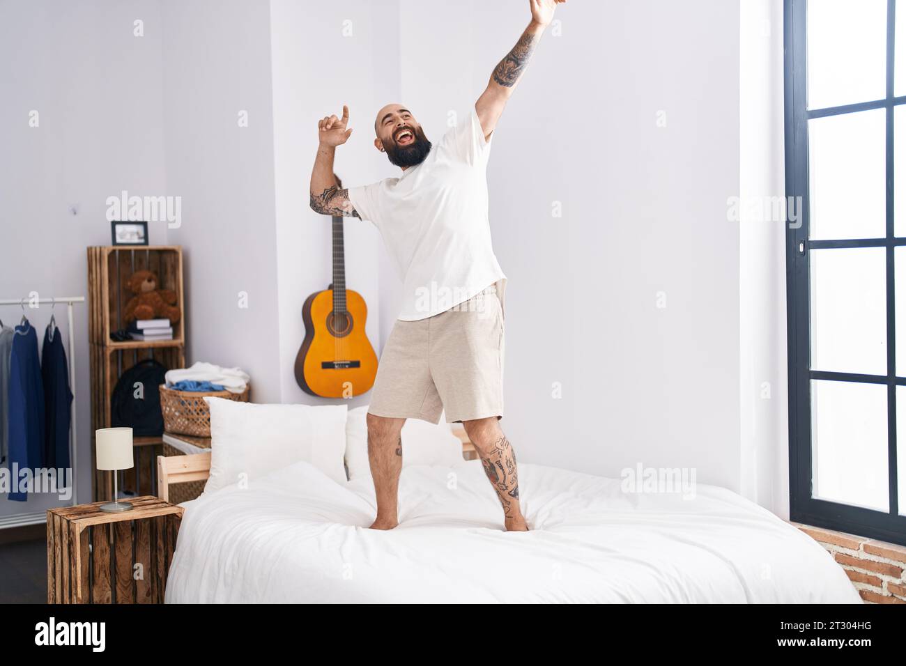 Young bald man smiling confident dancing on bed at bedroom Stock Photo ...