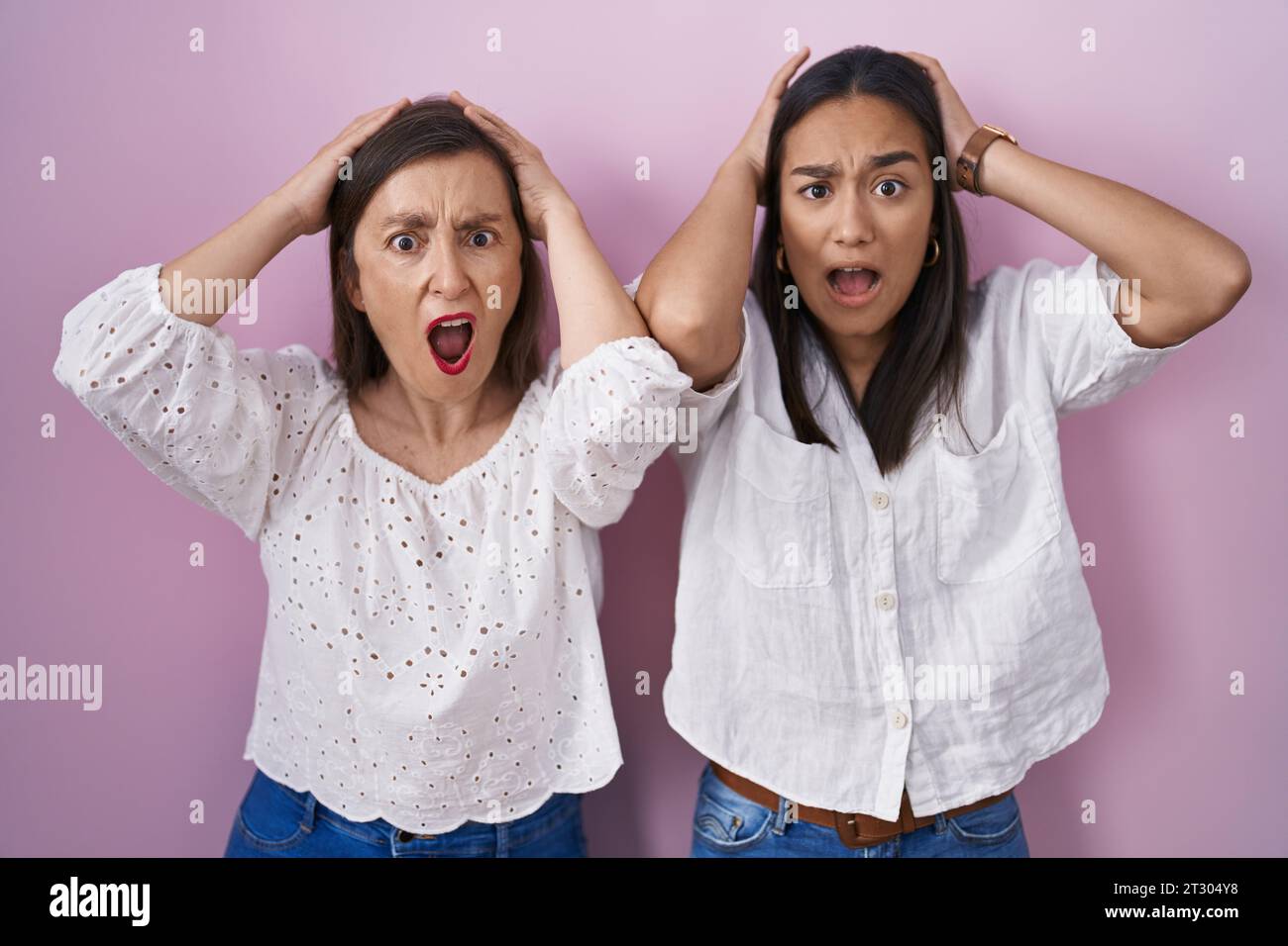 Hispanic mother and daughter together crazy and scared with hands on ...