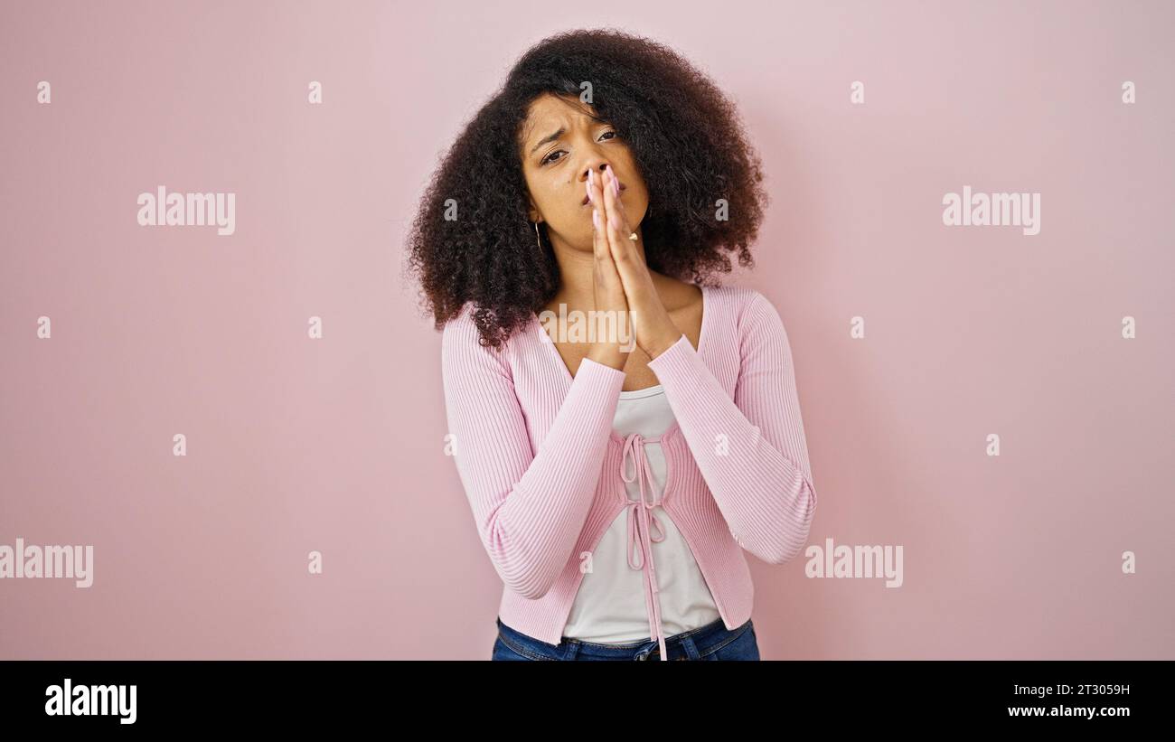 African american woman praying over isolated pink background Stock ...