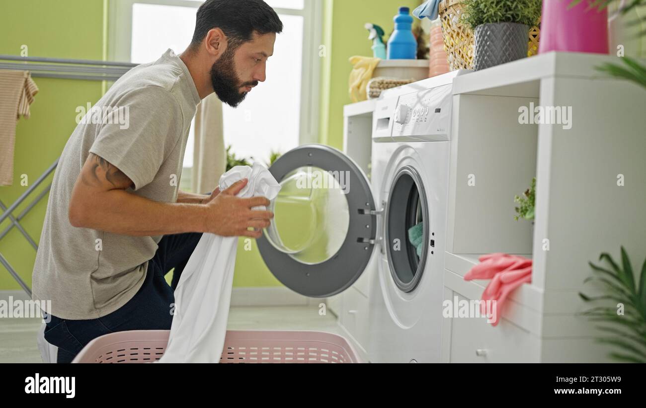 Young hispanic man washing clothes at laundry room Stock Photo - Alamy