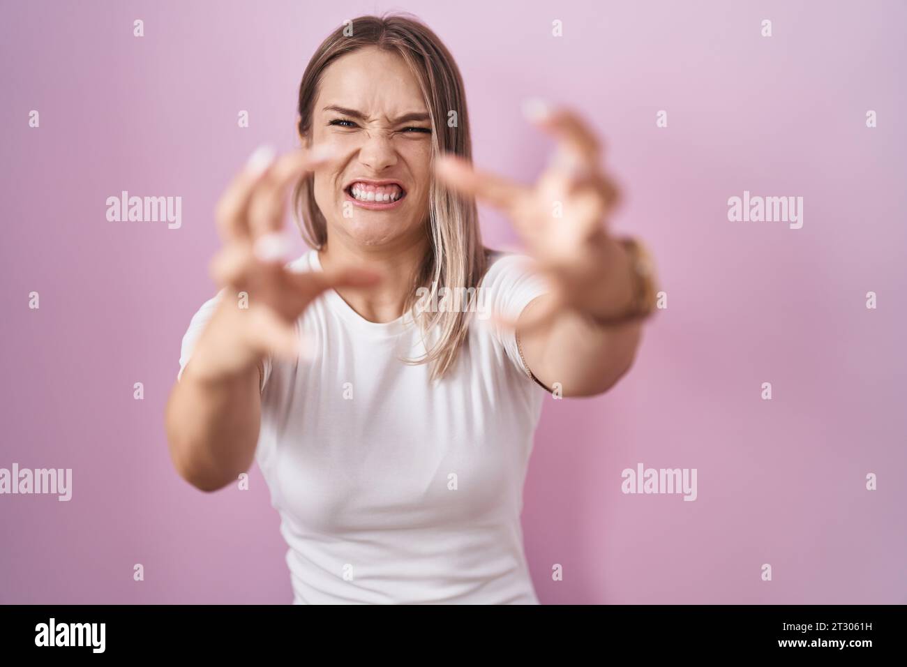 Blonde caucasian woman standing over pink background shouting ...