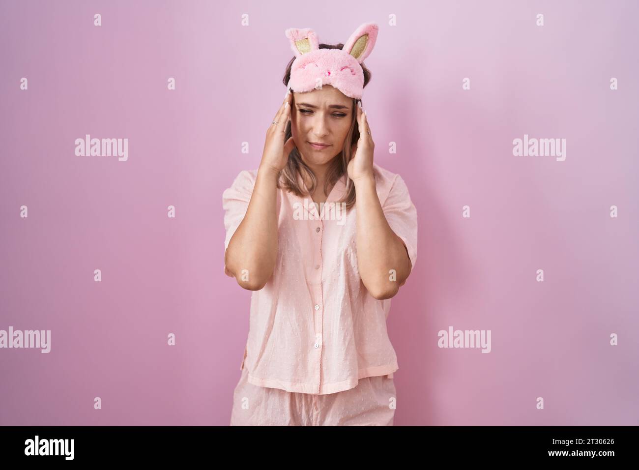 Blonde Caucasian Woman Wearing Sleep Mask And Pajama With Hand On Head