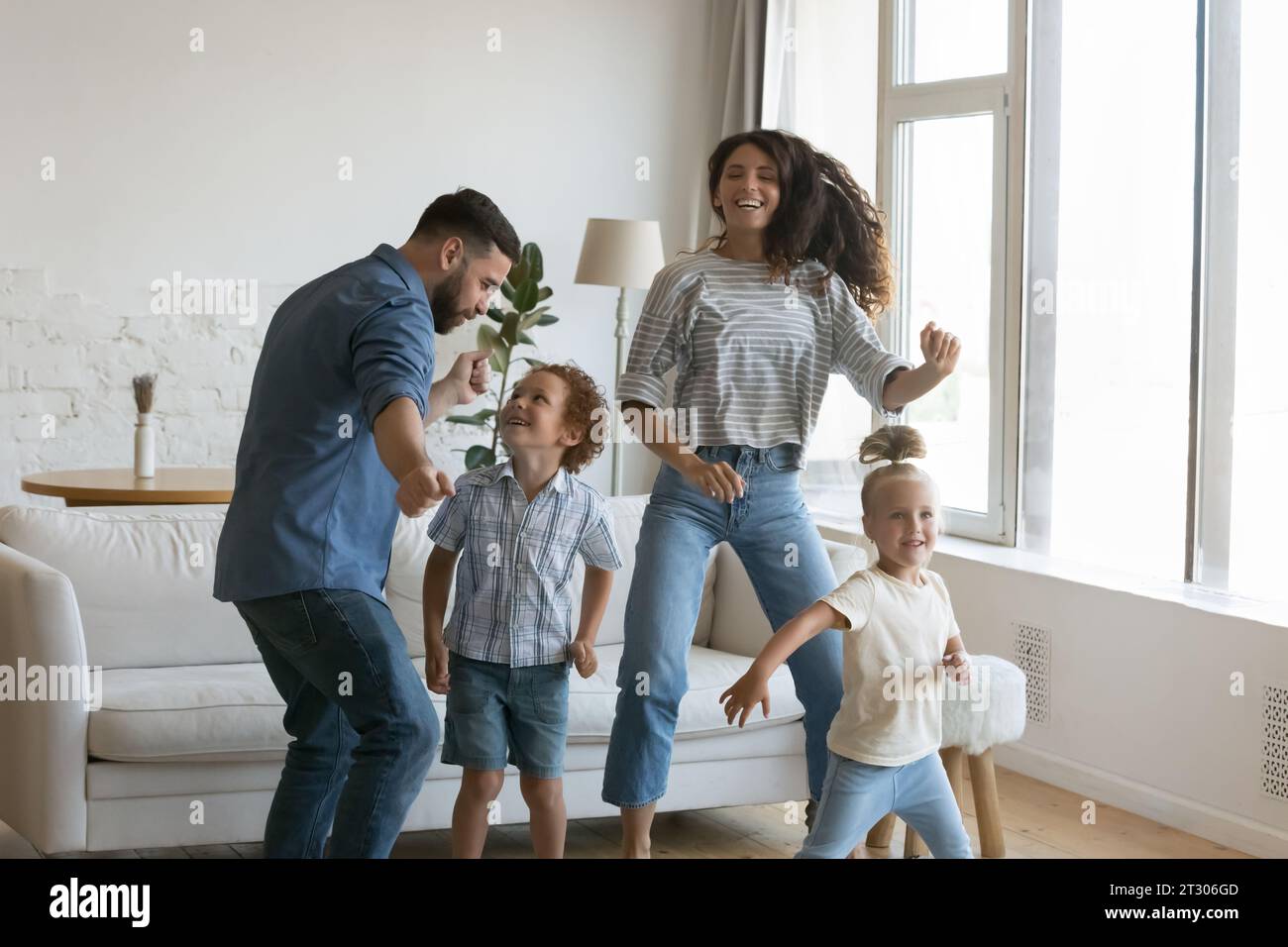 Cheerful couple of parents teaching little preschool kids to dance ...