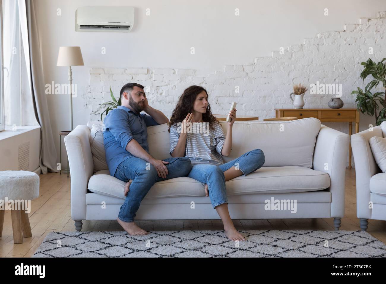 Frustrated adult millennial couple having problems with air conditioner ...