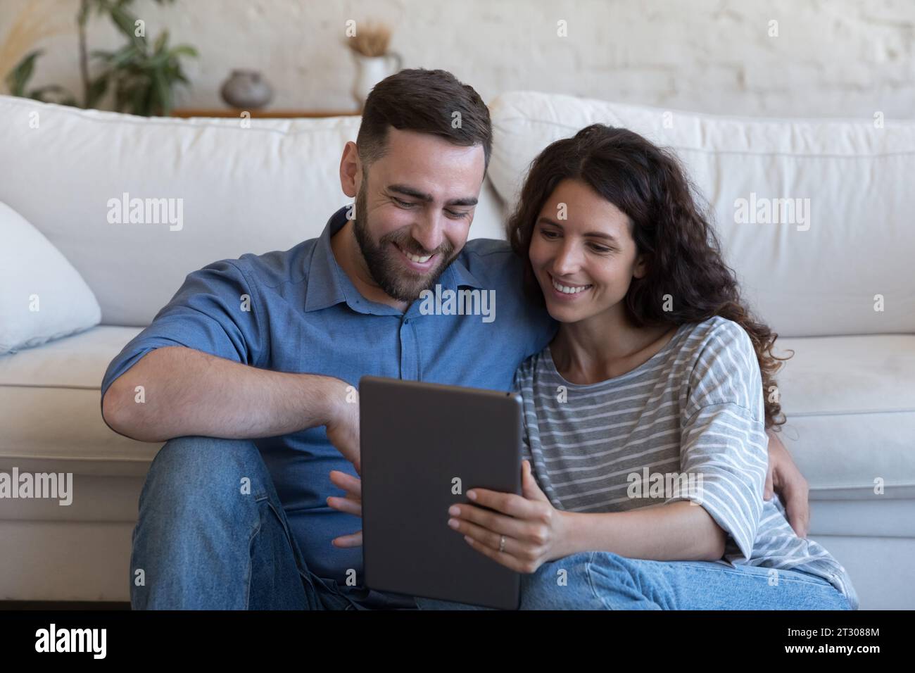 Happy husband and wife sharing tablet computer, enjoying communication ...