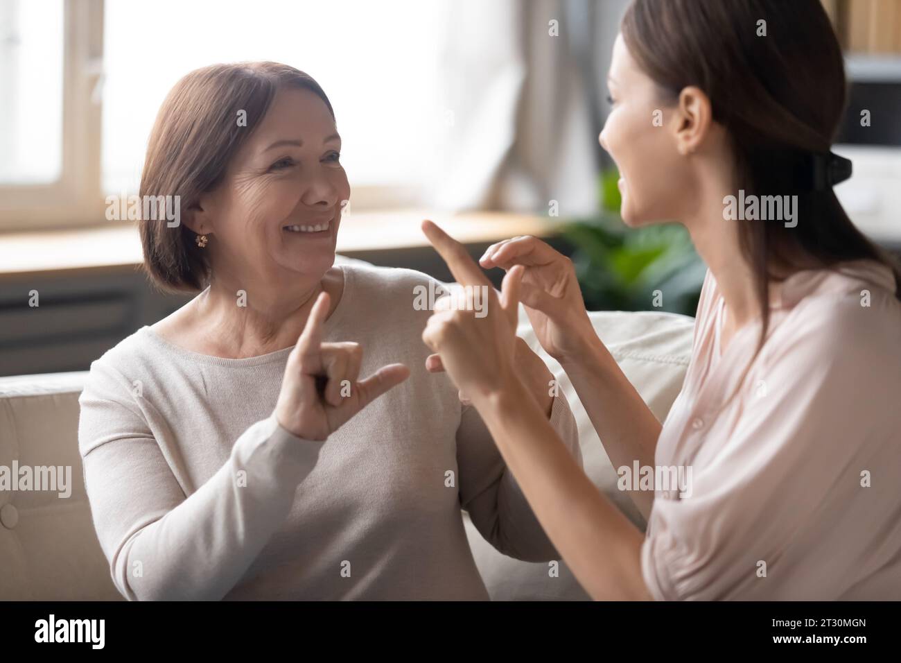 Elderly mother and adult daughter communicating using sign language ...