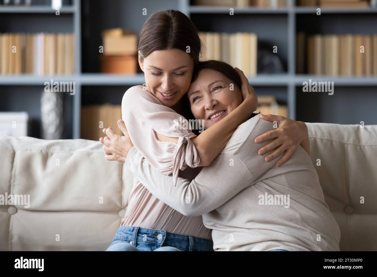 Adult daughter cuddling cherish her mother women seated on couch Stock Photo - Alamy