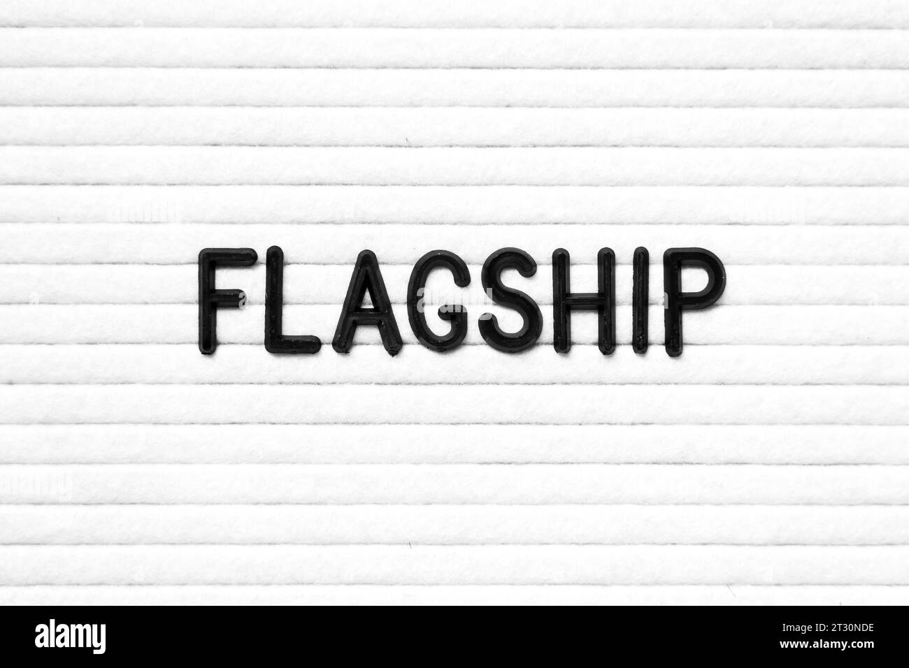 Black color letter in word flagship on white felt board background ...