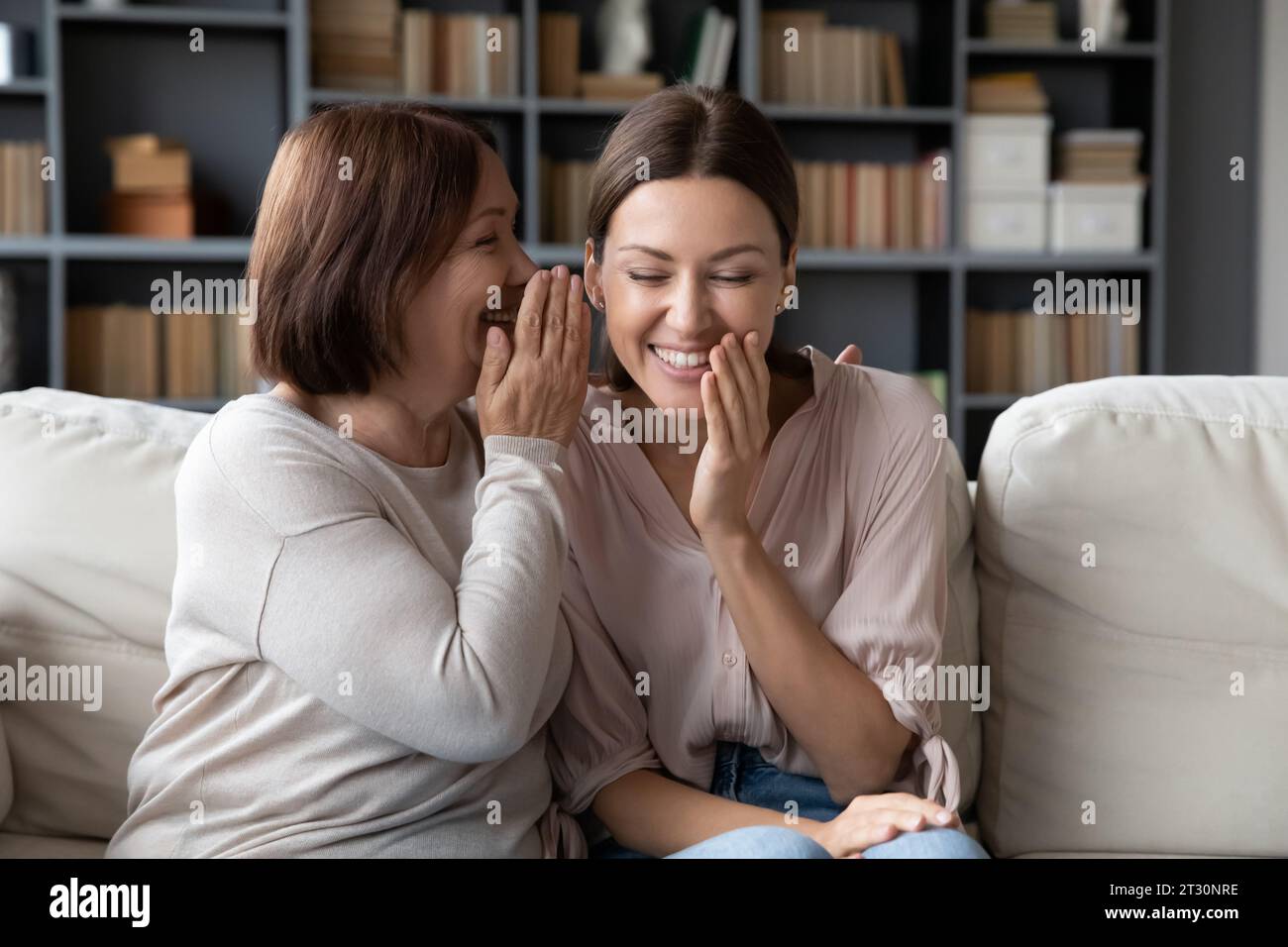 Elderly mother telling on ear to adult daughter a secret Stock Photo ...