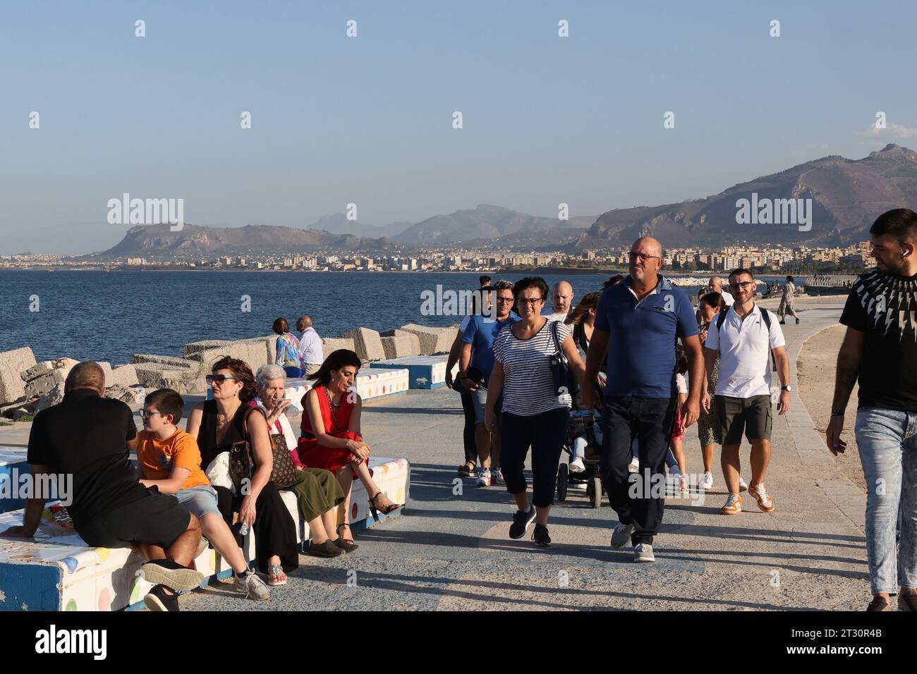 Pedestrians stroll along the promenade on the seafront at Palermo ...