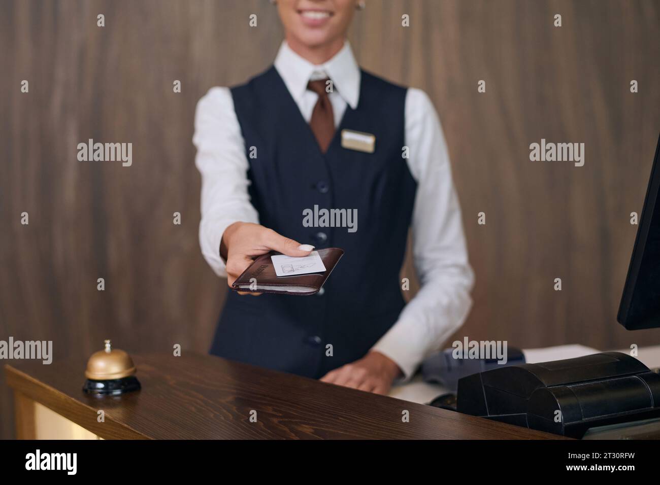 Smiling receptionist giving key from the room while standing behind the ...