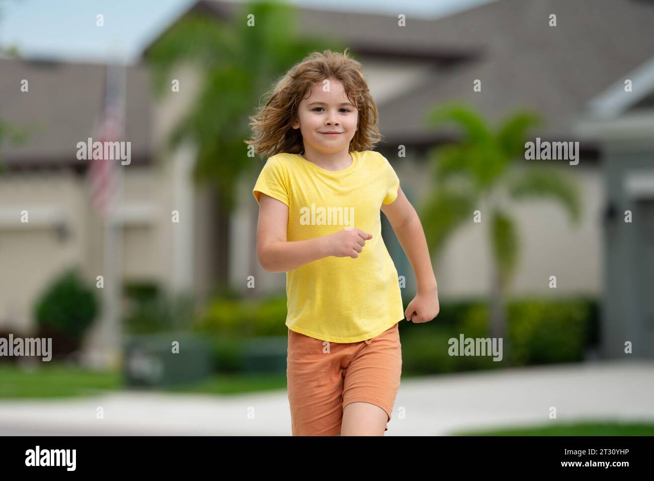 Cute kid boy running across american neighborhood street. Summer ...