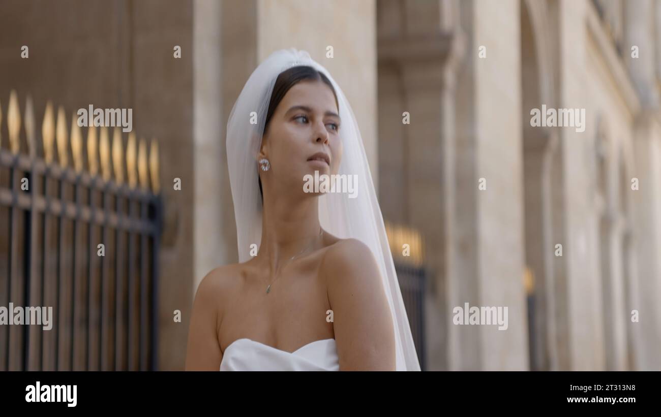 Slim graceful young brunette woman in wedding dress and white veil ...