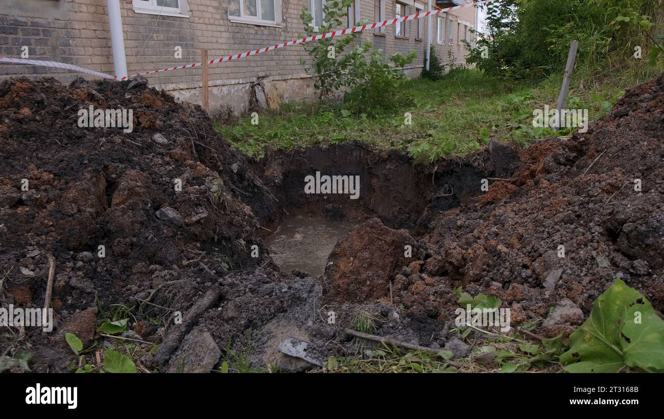 Dug dirty pit in ront of the house with grass behind. Clip. Repair ...