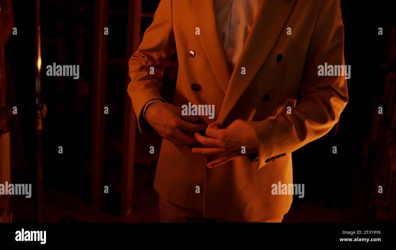 A man in a brown jacket fastens the buttons in a dark room. Stock ...