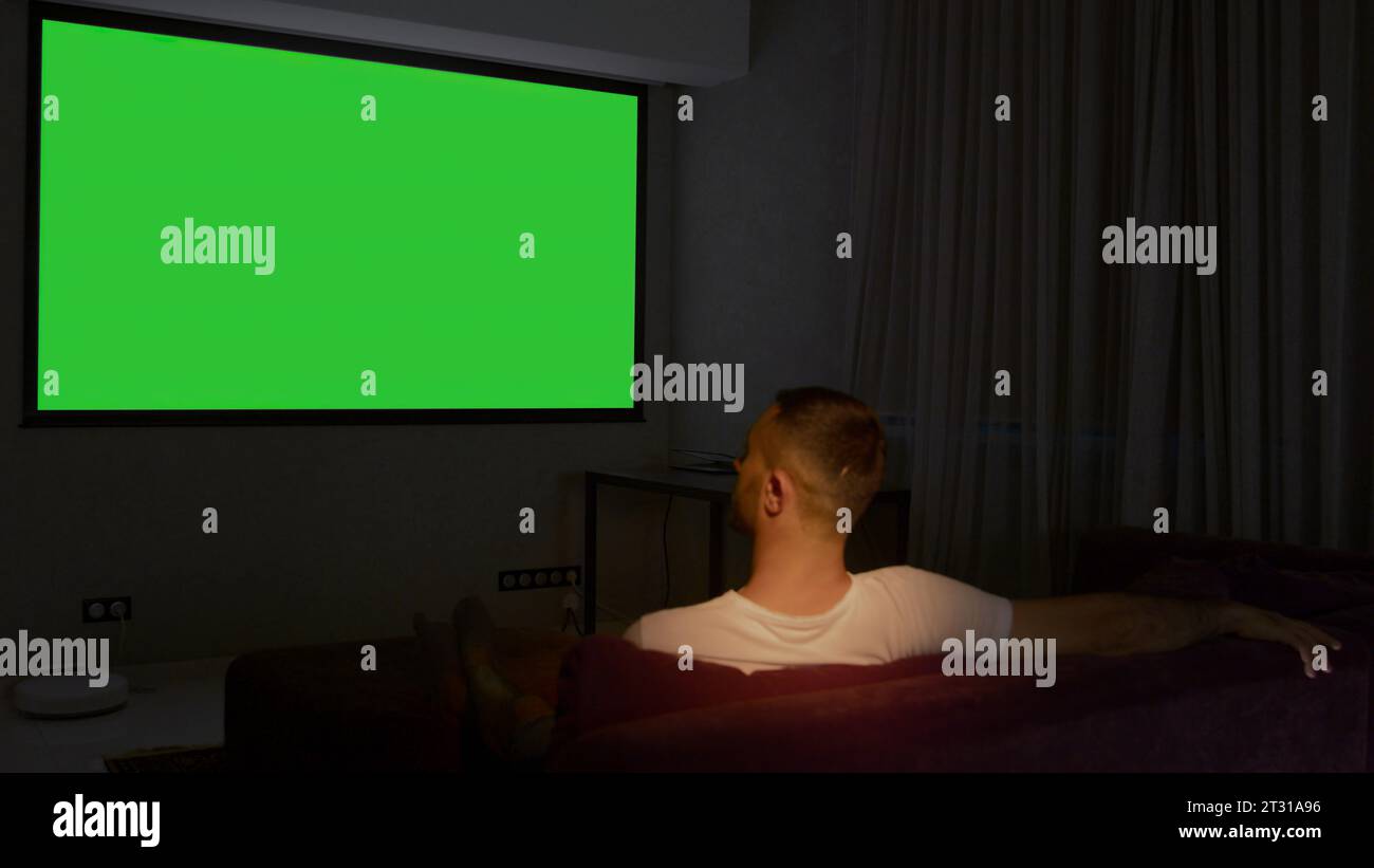 Viewing on a projector in a closed room. Media. A man looking into a ...