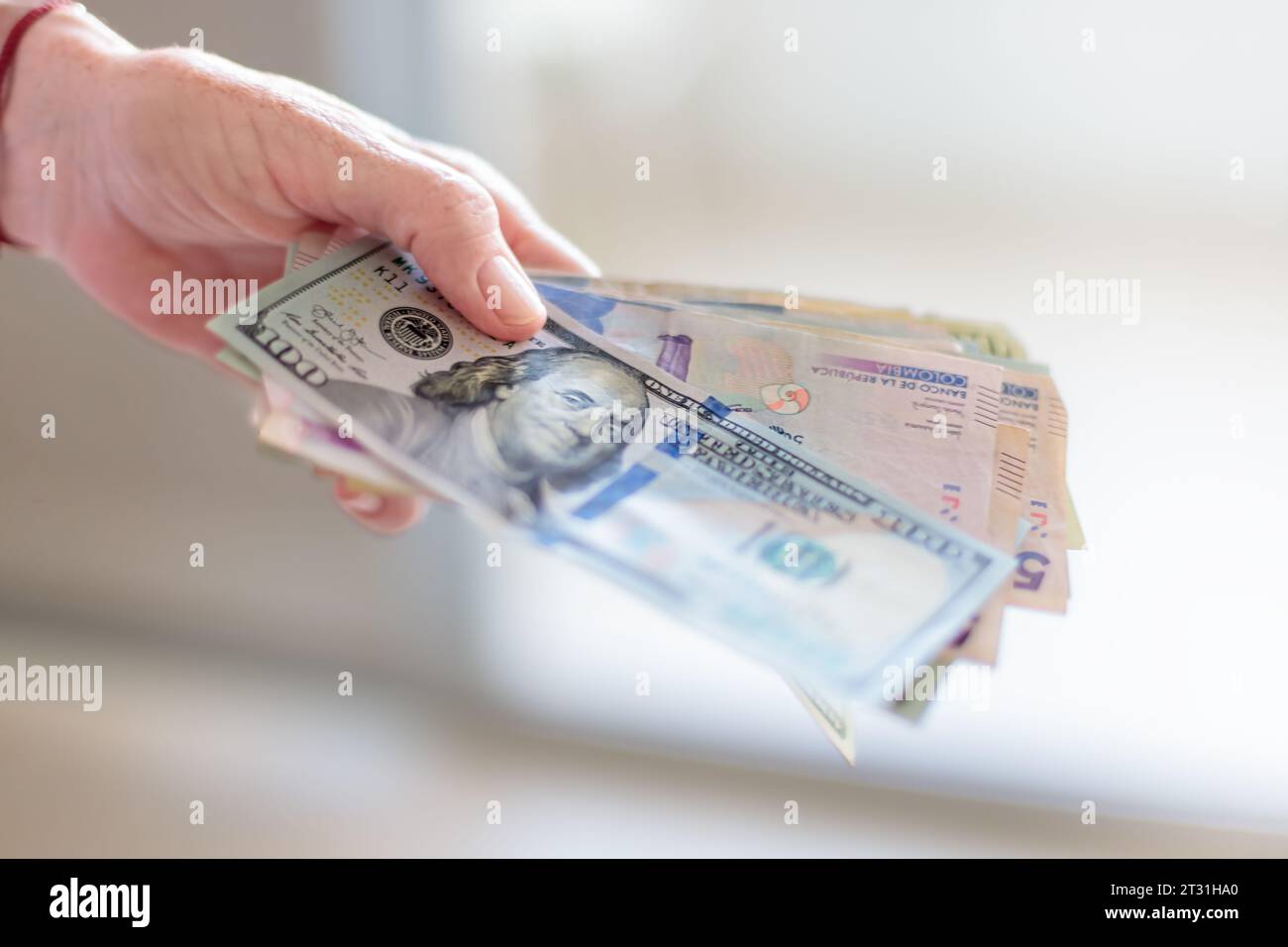 Close-up of woman's hands holding bills of 50 thousand Colombian pesos ...