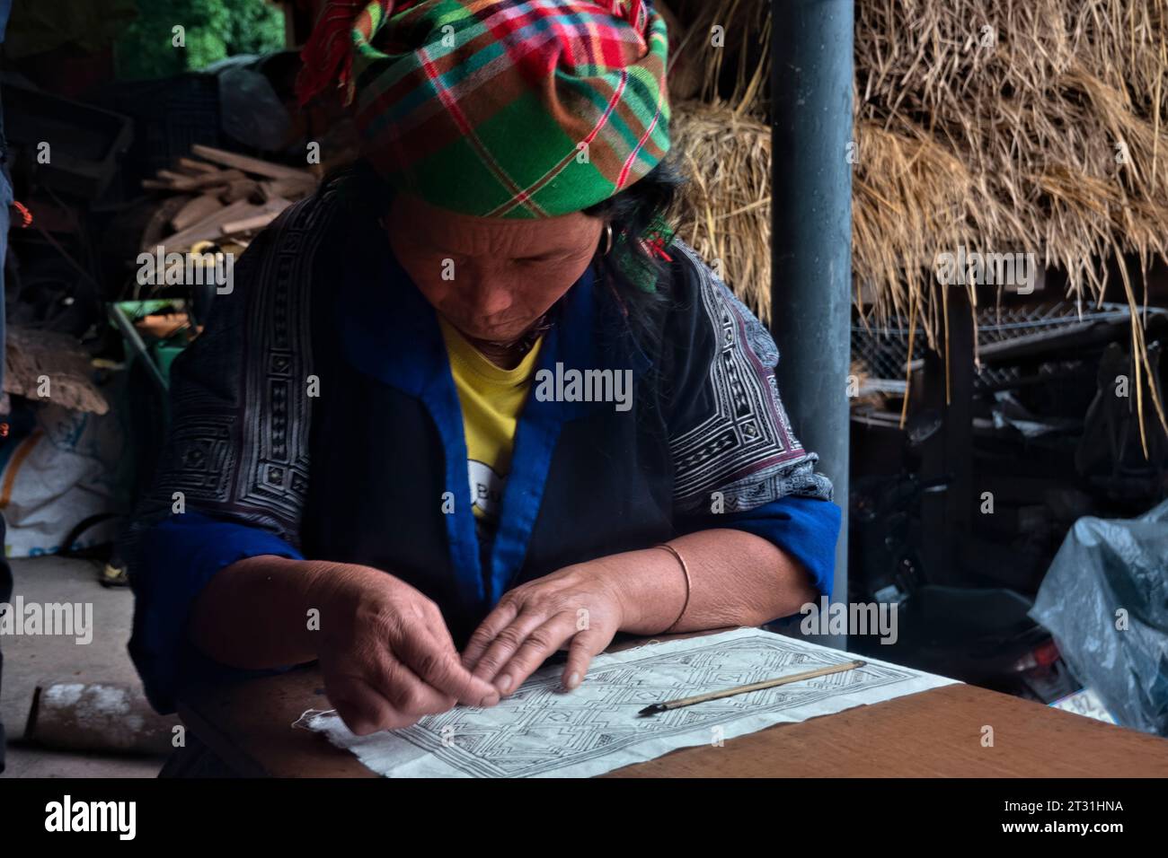 A Flower Hmong woman draws a pattern for her traditional embroidery, Mu ...