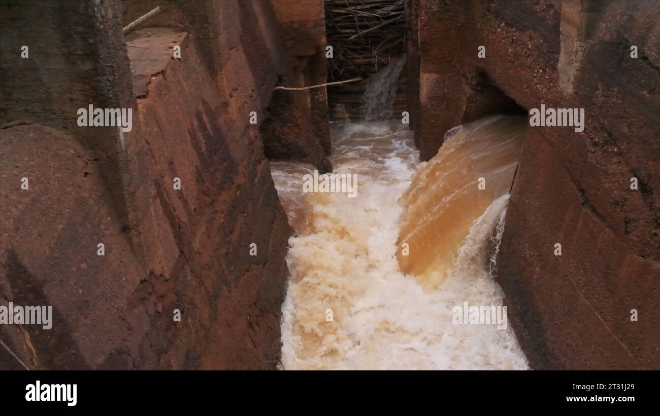 Slow motion of water flow of ancient dam. Clip. Dirty streams of water ...