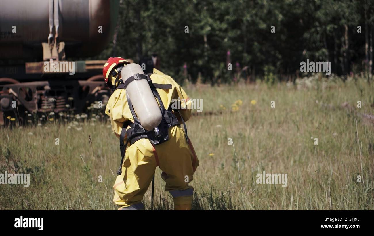 Man in fire suit in field. Clip. Firefighter puts up sign about danger ...