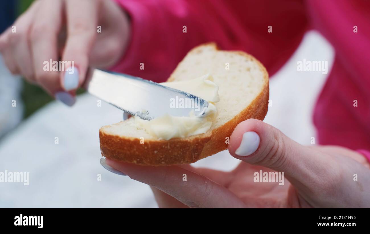 Close-up of woman spreading butter on bread. Clip. Thick piece of ...