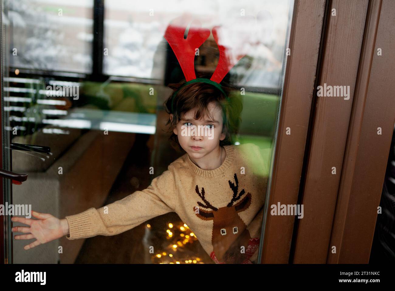 Child boy dressed in reindeer costume with antlers, standing near ...