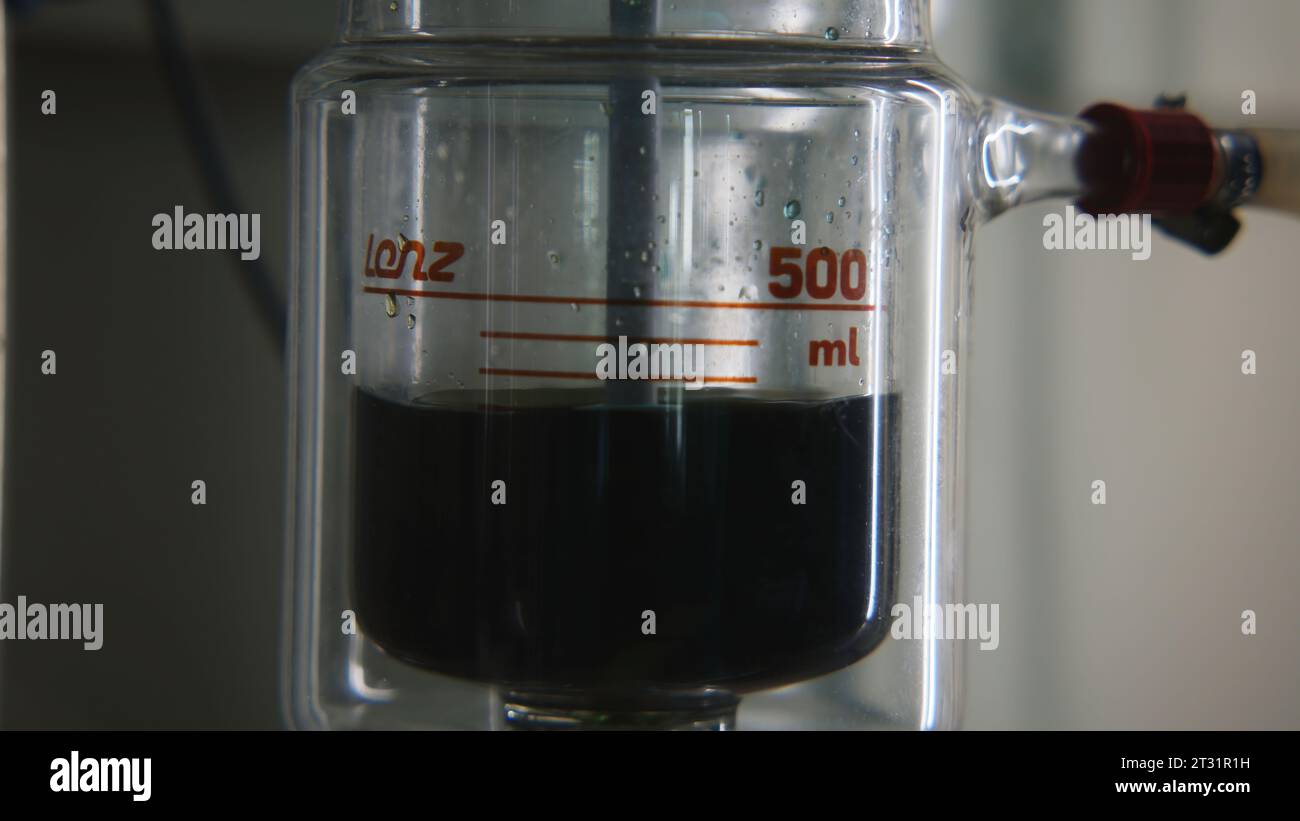 Rotating dark liquid in laboratory flask. Stock footage. Bubbling ...