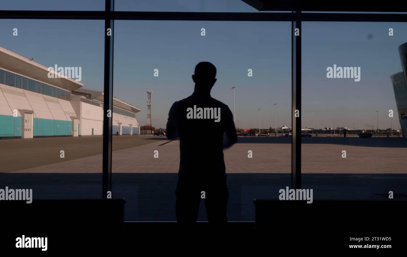 Rear view of a man silhouette at the shopping center going to the ...