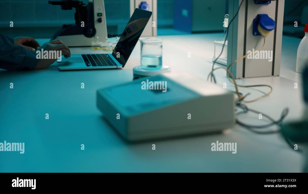Woman hands, laptop at the chemical lab with flask, microscope, and ...