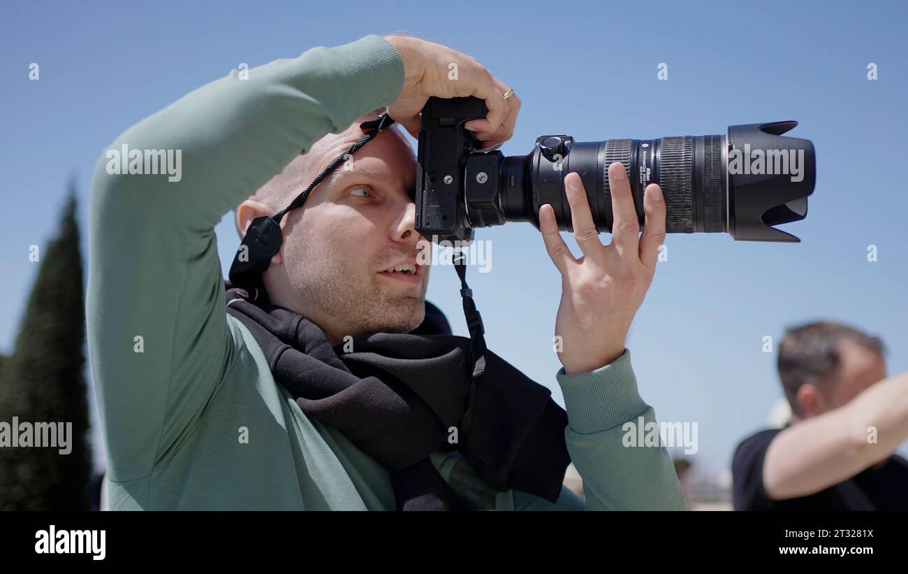 Side view of a male photographer with a professional camera outdoors ...