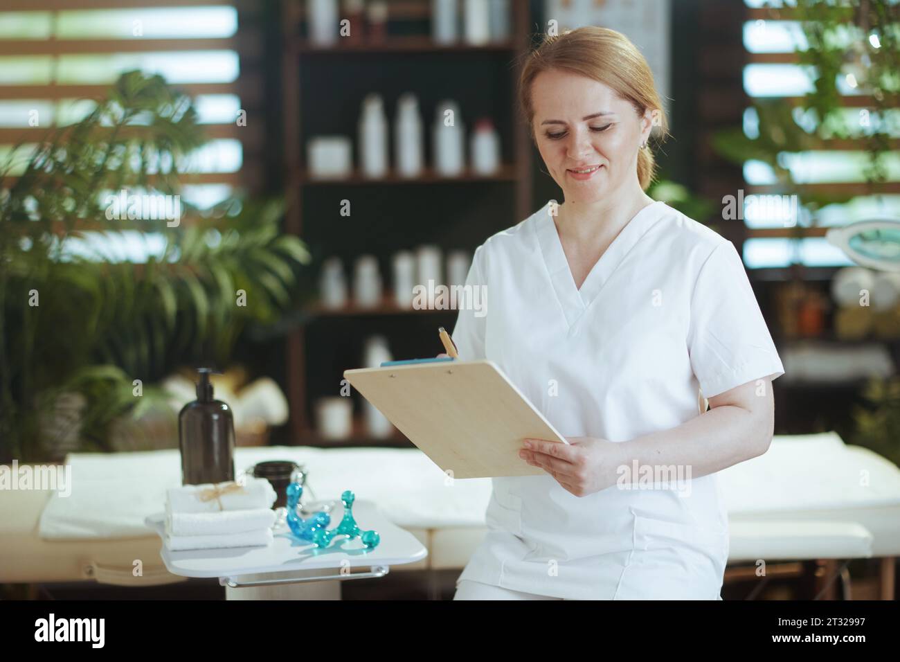 Healthcare time. female massage therapist in massage cabinet with clipboard Stock Photo - Alamy