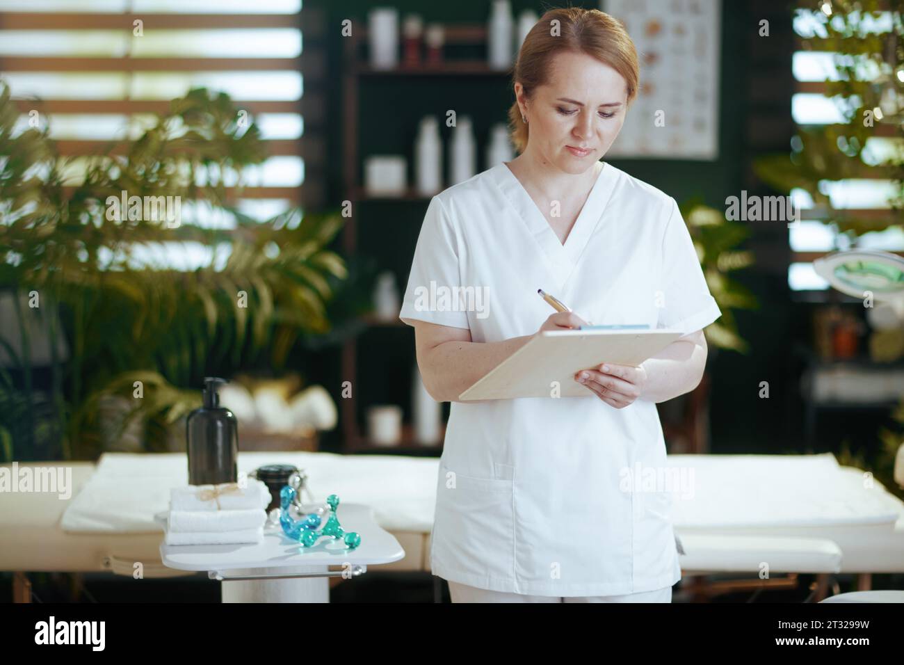 Healthcare time. female massage therapist in spa salon with clipboard Stock Photo - Alamy