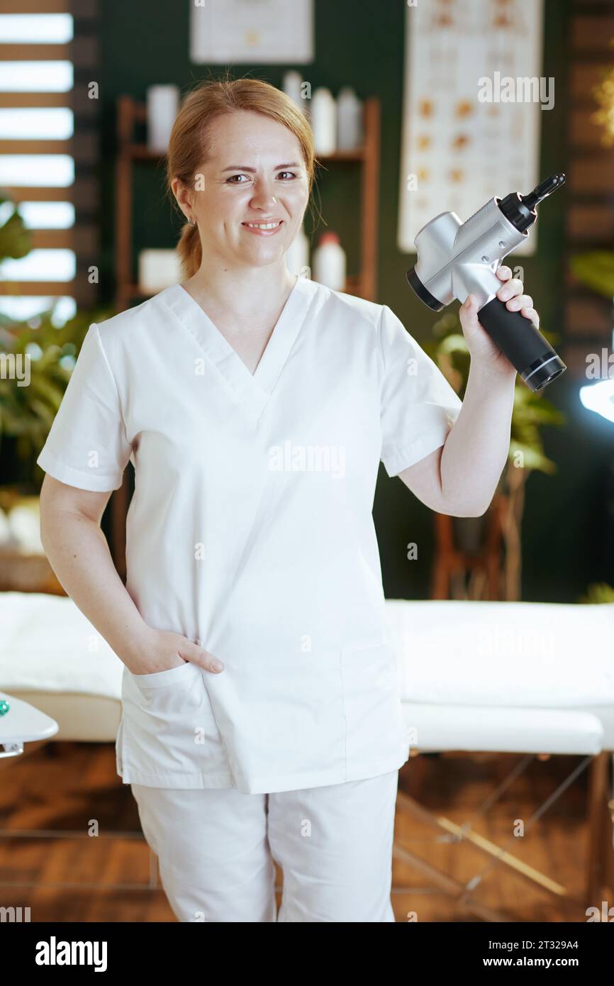 Healthcare time. happy female massage therapist in massage cabinet with massage pistol Stock ...