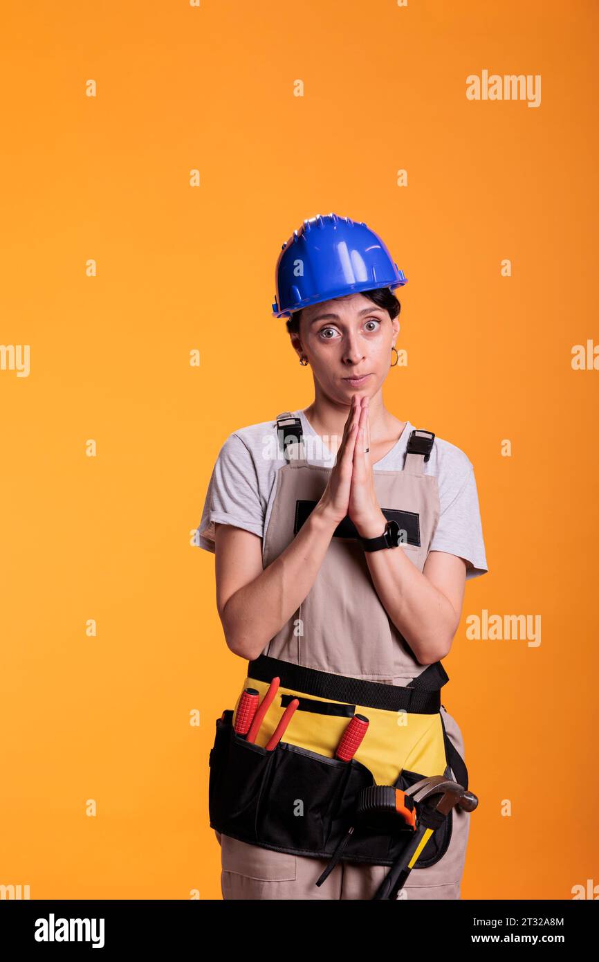 Female builder doing prayer hands sign on camera, begging and asking ...